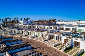 Um hotel com várias varandas, área de piscina e vista clara para o oceano.