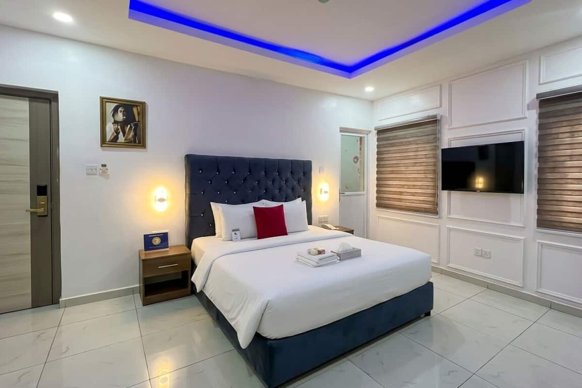 Um quarto moderno com uma cama grande, luminárias de cabeceira, uma TV de tela plana e um lustre.