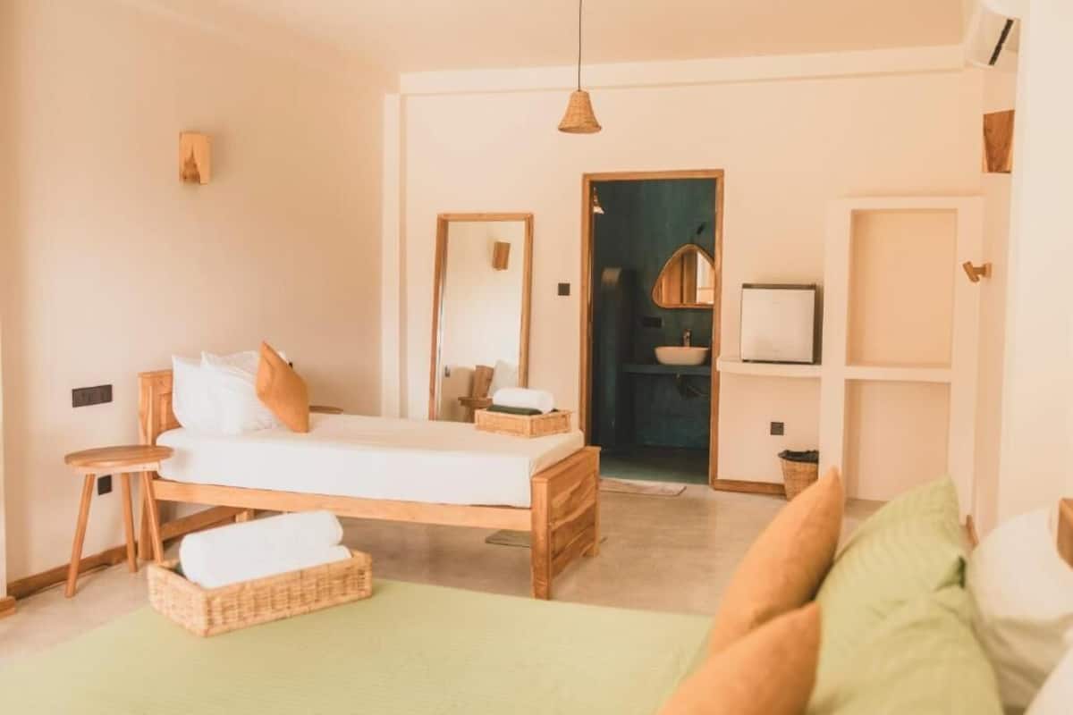 Quarto com cama, mesa de cabeceira, abajur e televisão.