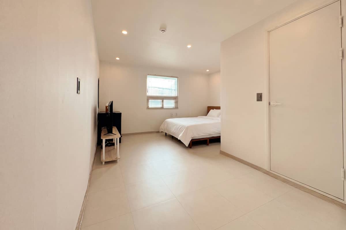Quarto com cama, escrivaninha, cadeira, janela e porta.