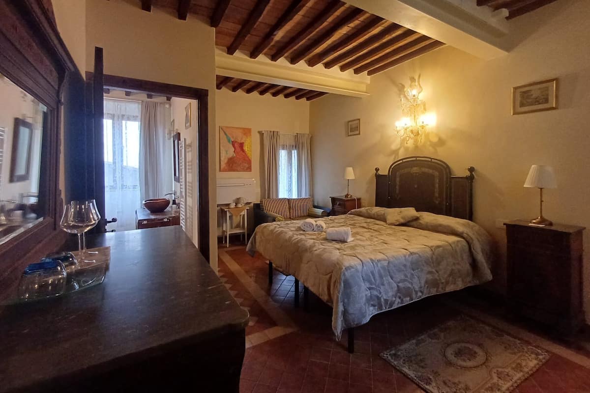 Quarto com cama, mesas de cabeceira, um candelabro e vista para o exterior.