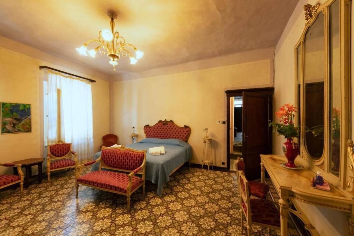 Quarto com cama, duas cadeiras, escrivaninha, espelho e lustre.