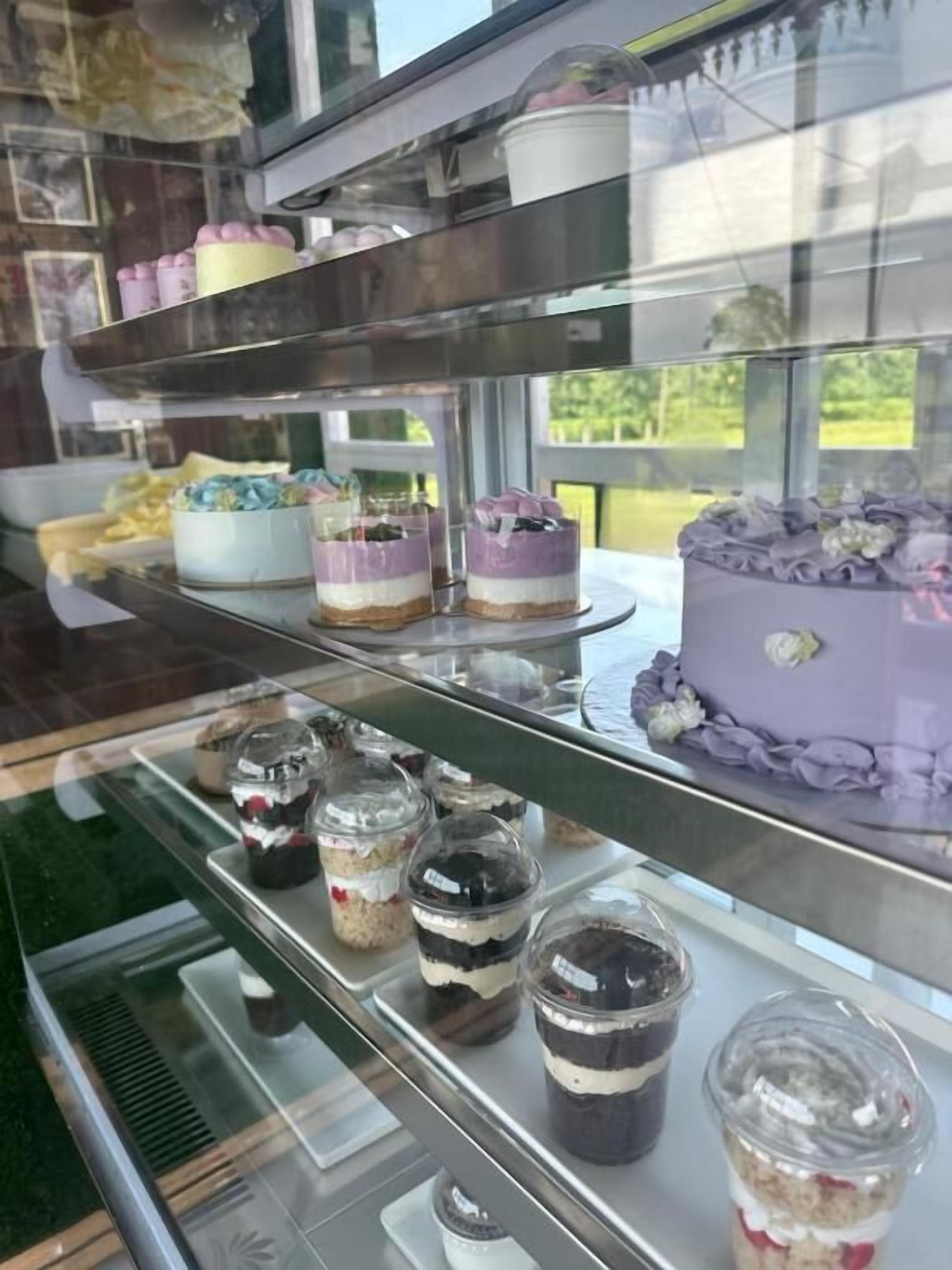 Vitrine com bolos em camadas e sobremesas de copo.