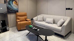 Uma sala de estar moderna com um sofá, uma mesa de centro, uma poltrona e um quadro na parede.