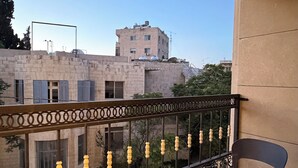 Uma varanda com duas cadeiras e uma mesa, com vista para um horizonte urbano com edifícios.
