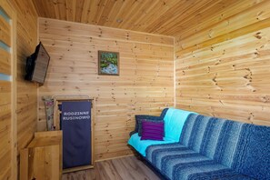 Interior de uma cabana de madeira com um sofá, um quadro e uma placa com a inscrição 'RODZINNE RUSINOWO'.