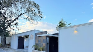 Um edifício moderno com garagem, um pequeno jardim e uma parede externa branca.