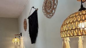 Quarto com cabeceira de madeira, uma peça de roupa preta pendurada e duas luminárias fixadas na parede.