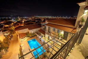 Piscina no terraço com vista da cidade à noite.