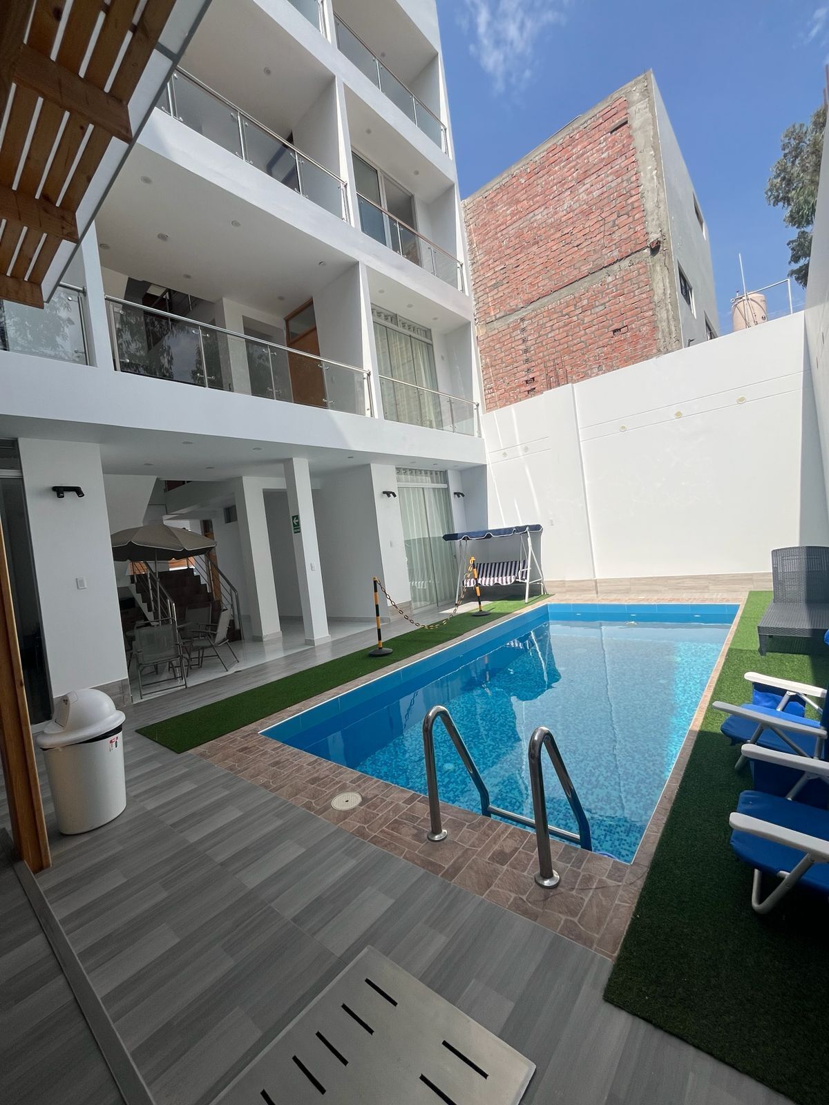 Um edifício moderno com piscina no terraço, área de estar externa e parede de tijolos.