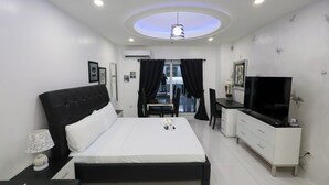 Quarto de hotel moderno com cama, televisão, escrivaninha e cadeira.