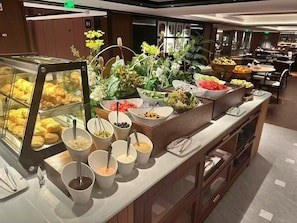 Buffet com diversos alimentos e um expositor de vidro.