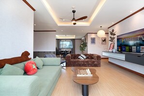 Uma sala de estar moderna com um sofá, uma mesa de centro com um jogo de xadrez, uma televisão e um ventilador de teto.