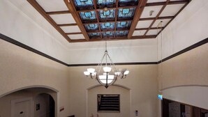 Um hall de entrada com um candelabro, uma lareira e um tapete estampado.