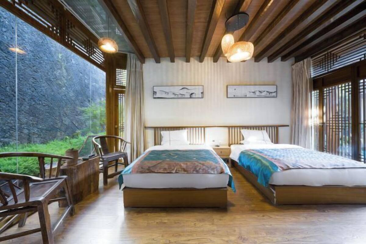 Quarto com duas camas, móveis de madeira e obras de arte nas paredes.