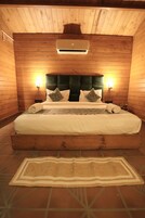 Um quarto com painéis de madeira, uma cama, duas luminárias na parede e um aparelho de ar condicionado.