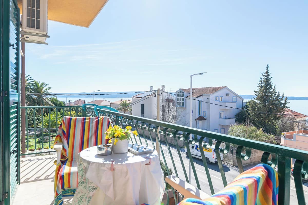 Uma varanda com mesa, cadeiras e vista para o mar e edifícios.