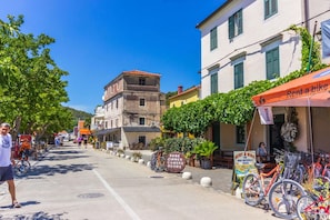 Rua com edifícios, placa de aluguel de bicicletas e placa com 'SOBE ZIMMER GAMERE ROOMS'.