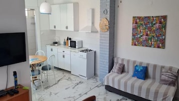 Um espaço compacto com cozinha compacta, área de jantar e sofá com almofadas.