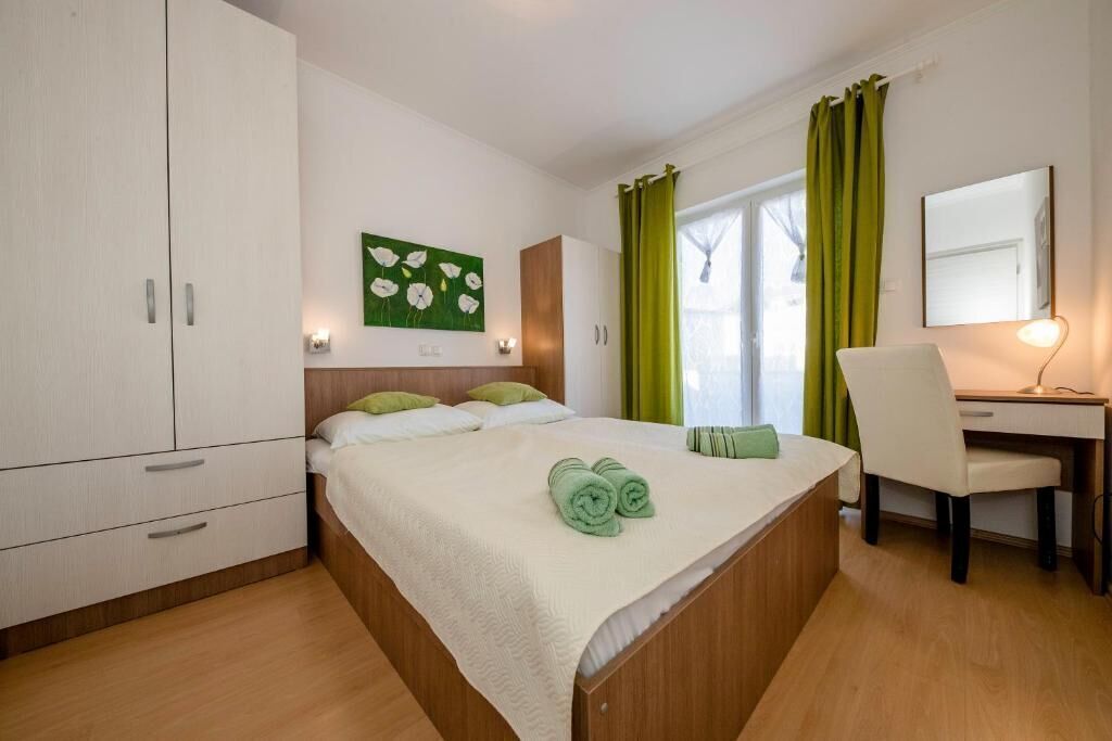 Quarto com cama, escrivaninha, cadeira, guarda-roupa e uma pintura de parede verde.
