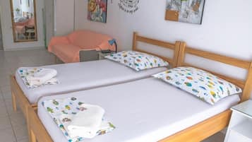 Uma cama de casal com roupa de cama branca e almofadas coloridas, uma cabeceira de madeira, uma mesa de cabeceira e um espelho.