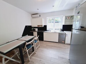 Uma cozinha compacta com mesa de jantar, cadeiras, fogão, pia e geladeira.