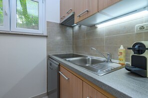 Uma cozinha com lava-louças embutida, uma pia dupla e uma máquina de café.