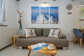 Uma sala de estar aconchegante com um sofá, mesa de centro e uma pintura com cenas de pesca.