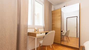 Quarto com escrivaninha de madeira, uma cadeira, cama, guarda-roupa e espelho.