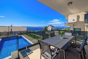 Varanda com piscina, área de estar externa e vista para o mar.
