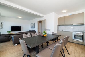 Uma sala de estar moderna com uma mesa de jantar escura, sofás cinzas e uma televisão de tela plana.