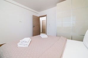 Quarto de hotel com cama, guarda-roupa e porta que dá para outro cômodo.
