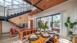Um interior moderno com área de refeições, escada e sala de estar.