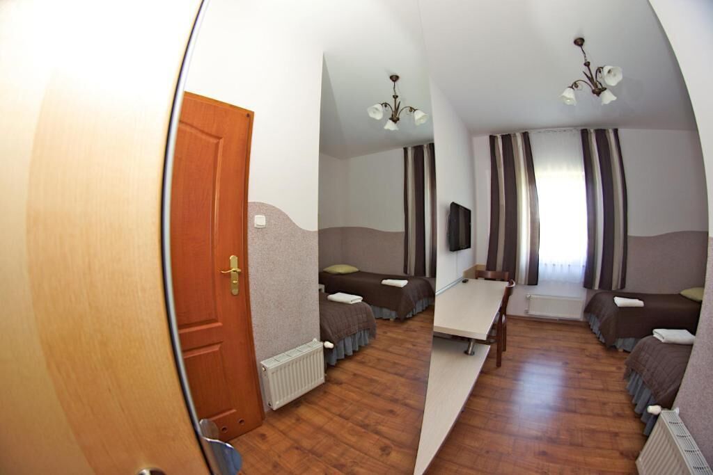Quarto com porta de madeira, uma cama, uma mesa, uma cadeira e uma televisão.