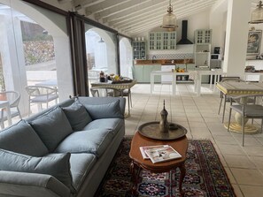 Uma sala ampla com um sofá cinzento, uma mesa de centro e um tapete estampado.