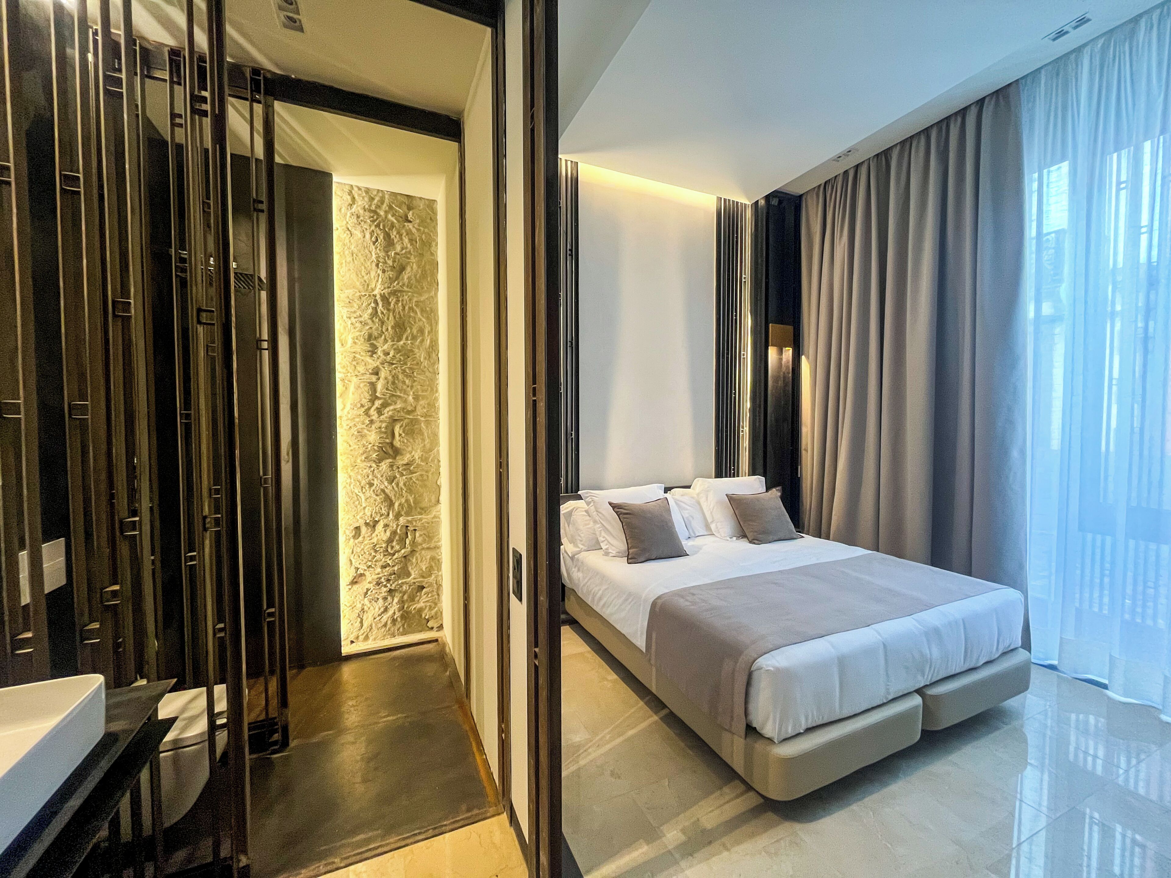 Quarto de hotel moderno com uma cama grande, um closet espaçoso e vista para o exterior.