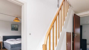 Uma escadaria com corrimãos de madeira que leva a um quarto com uma cama e um quadro na parede.