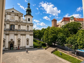 Um edifício histórico com uma torre imponente e uma grande praça aberta.