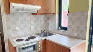 Uma cozinha compacta com forno embutido, micro-ondas e pia, armários de madeira e uma janela com vista.