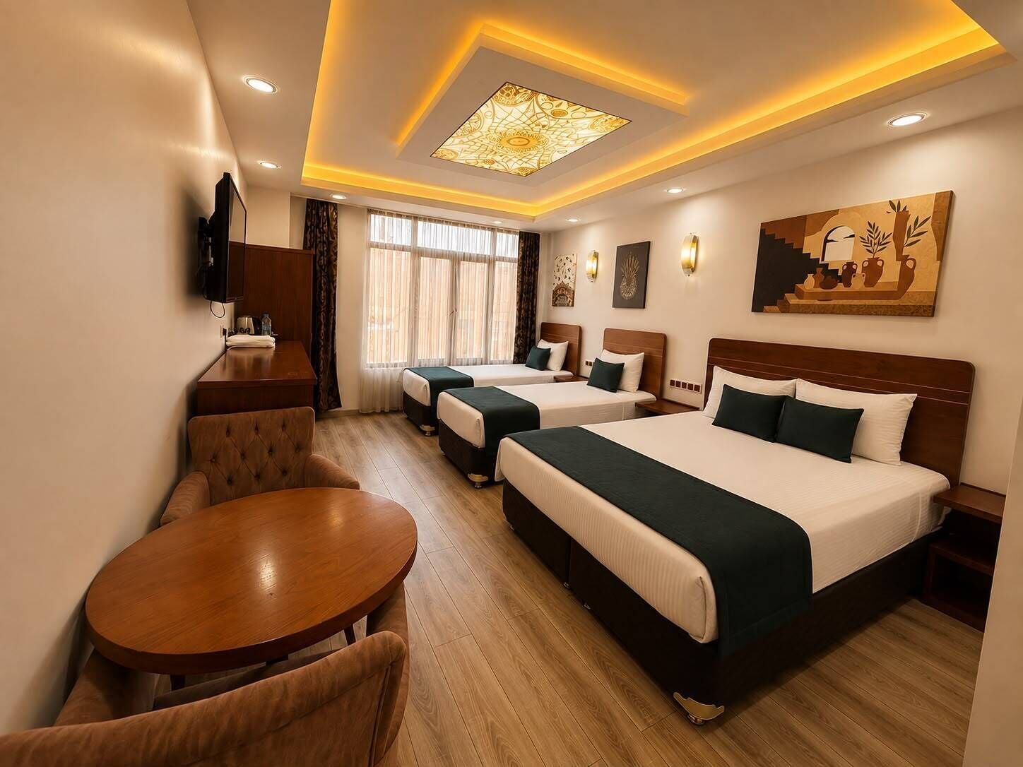 Quarto de hotel com duas camas, uma escrivaninha, uma cadeira e uma janela grande.
