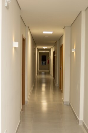 Um corredor comprido e estreito com portas em ambos os lados, dando acesso a quartos.