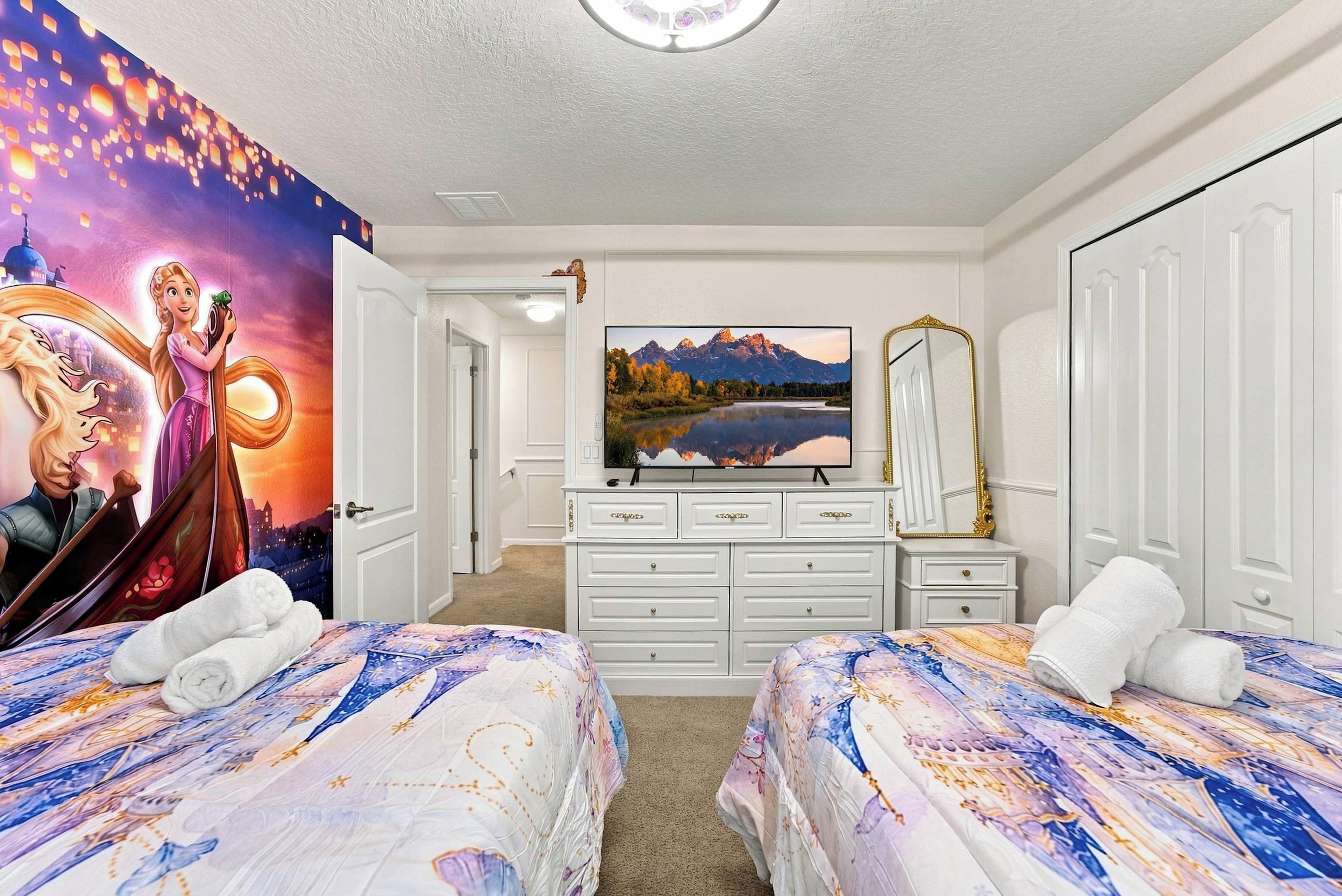 Quarto com duas camas, televisão, penteadeira e uma grande janela com vista para as montanhas.