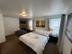 Quarto de hotel com uma cama grande, televisão de tela plana, lareira e janela com cortinas.