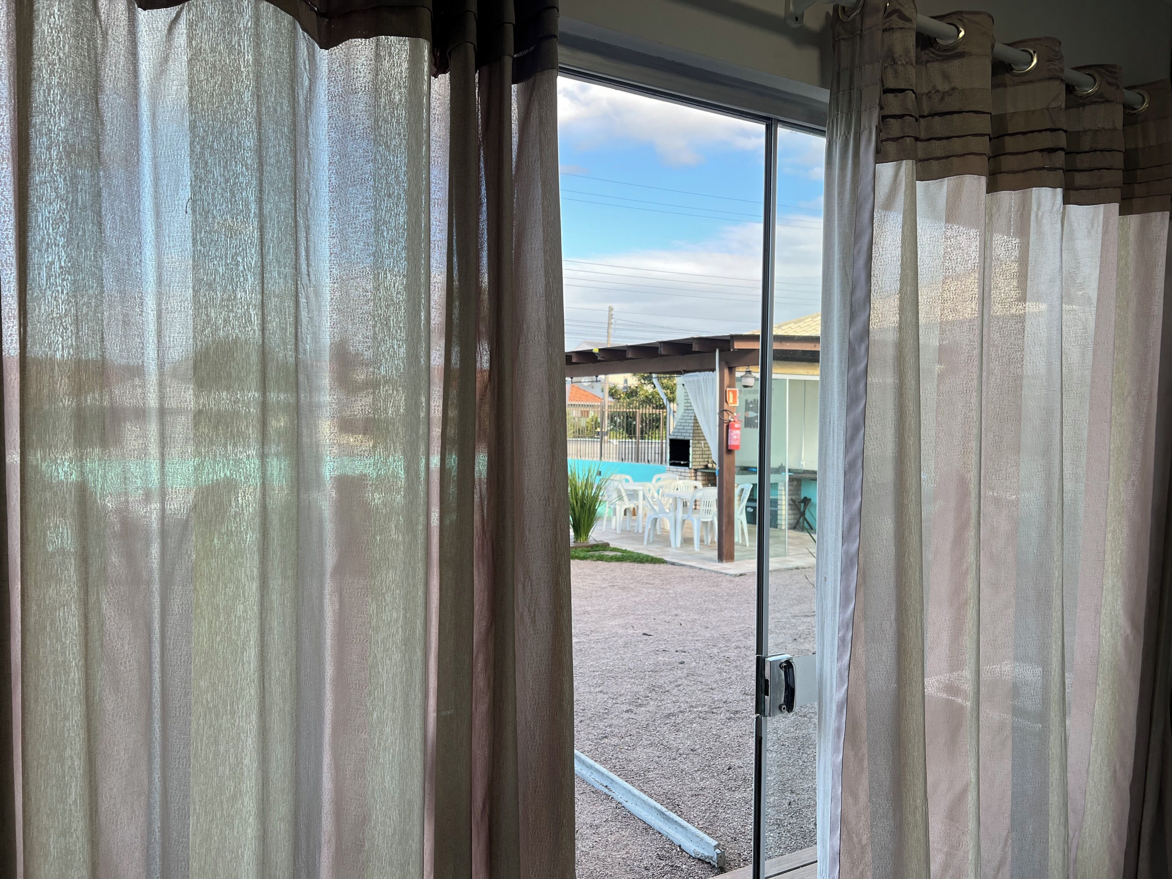 Quarto com porta de vidro deslizante que dá para um pátio exterior com piscina e mobiliário de exterior.
