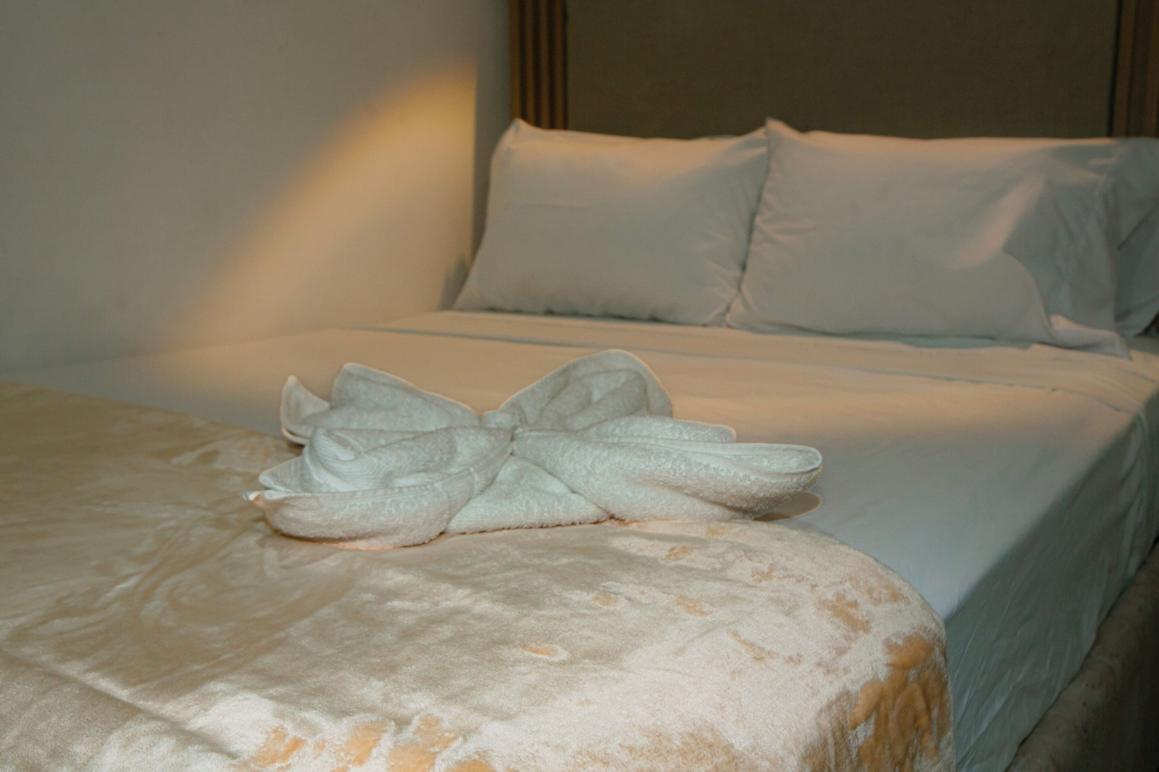 Uma cama bem arrumada com uma toalha e um laço na colcha.