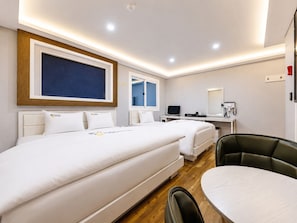 Quarto de hotel com duas camas, uma escrivaninha, uma cadeira, televisão e uma janela grande.