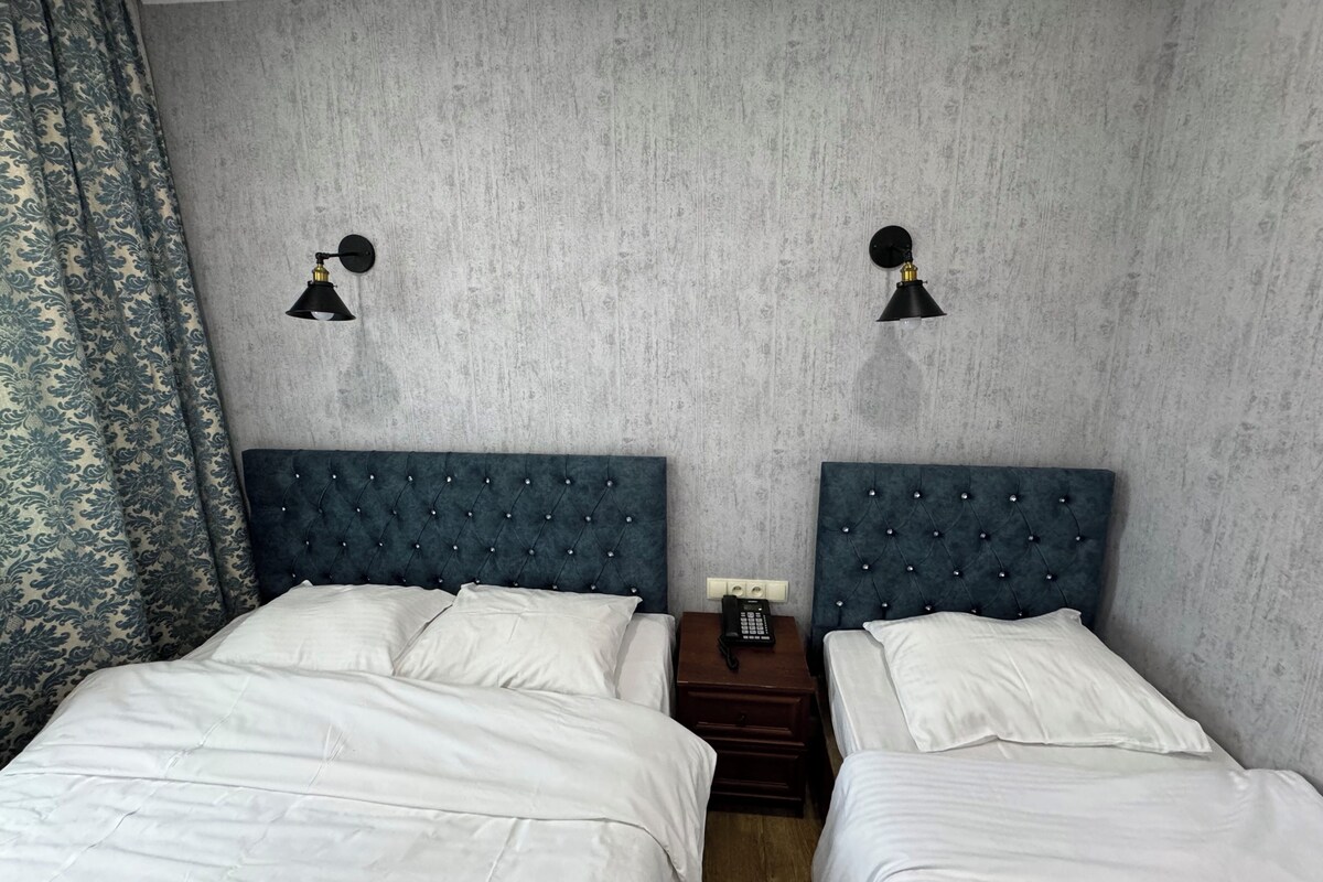 Quarto de hotel com duas camas, um telefone e duas luminárias fixadas na parede.