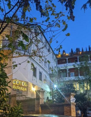 Um hotel com uma placa indicando 'HOTEL RALANGA', fachada de tijolos e uma varanda com grades.