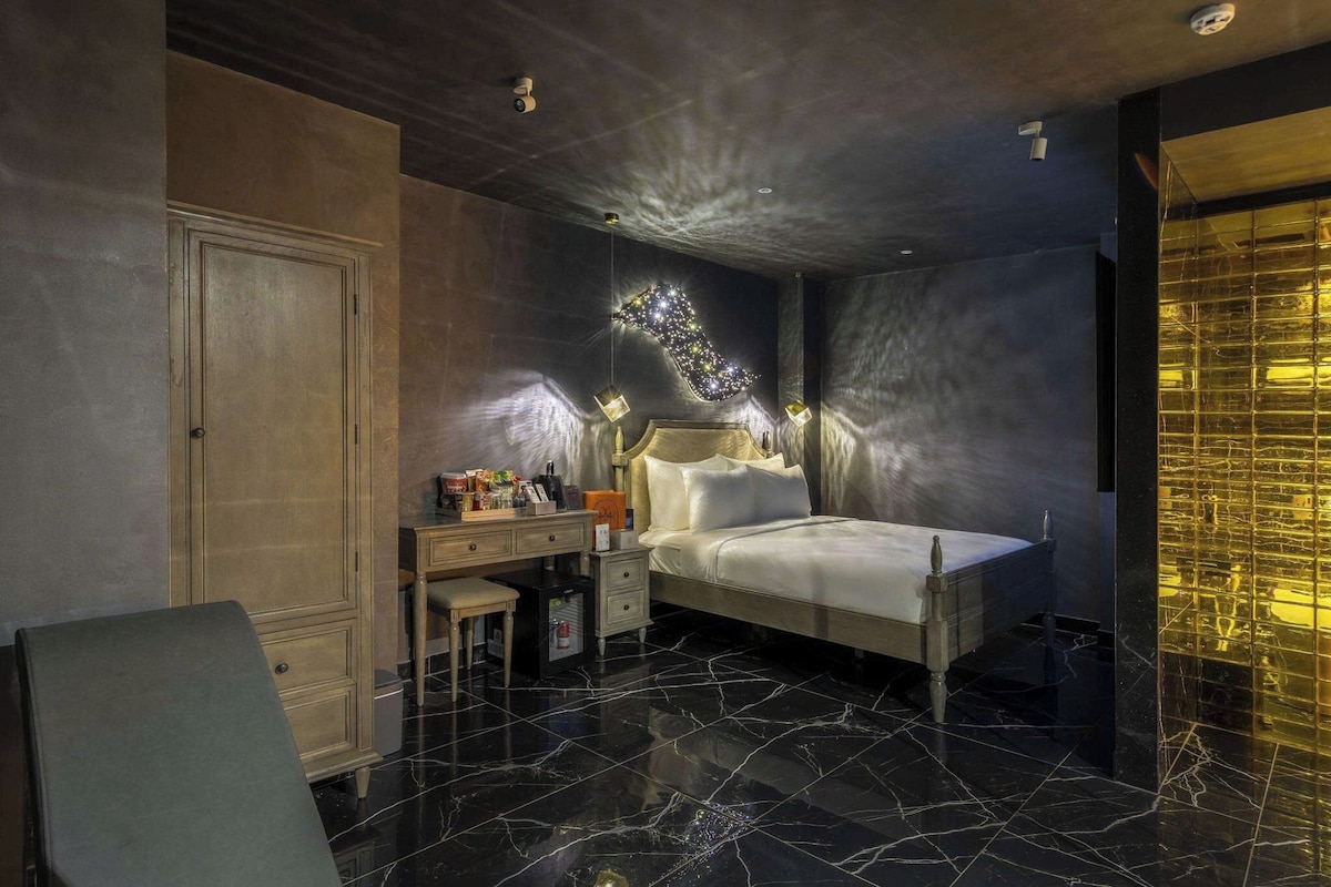 Quarto moderno com cama, mesas de cabeceira, escrivaninha e guarda-roupa.