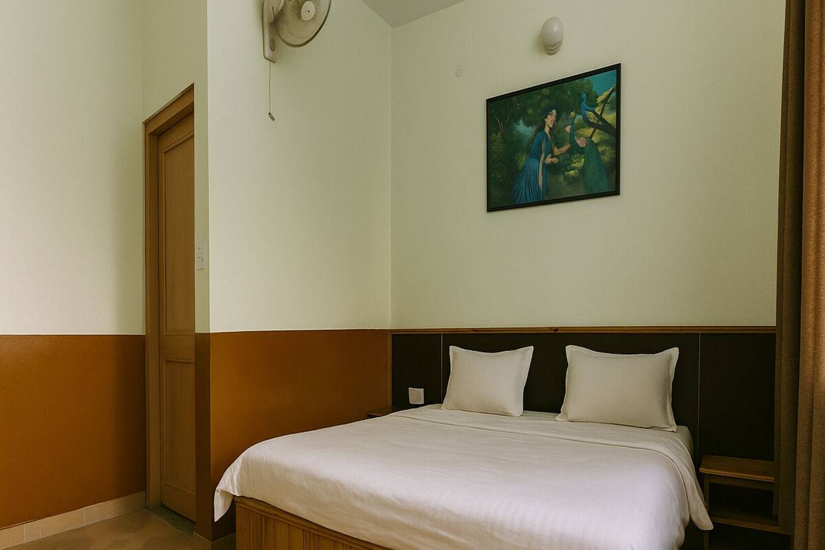 Quarto com cama de madeira, um quadro na parede e uma porta.